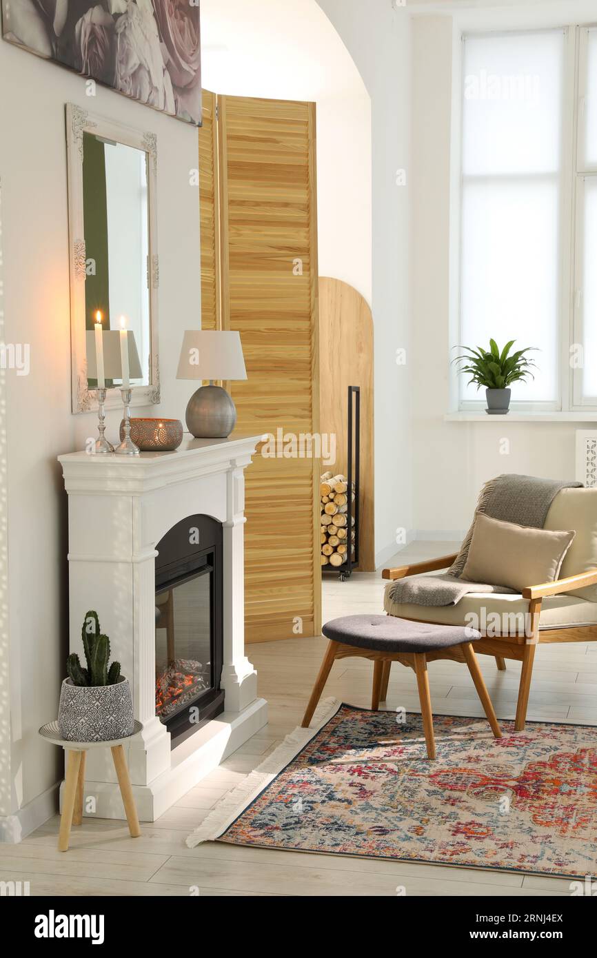 Stylish living room with beautiful fireplace, armchair and ottoman ...