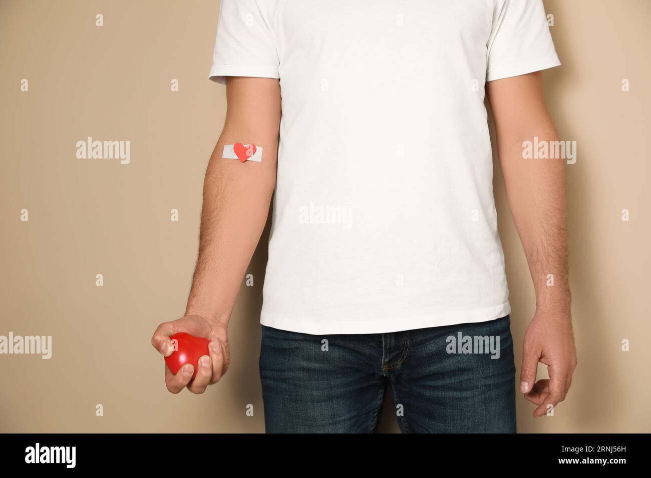 Blood donation concept. Man with adhesive plaster on arm holding red ...