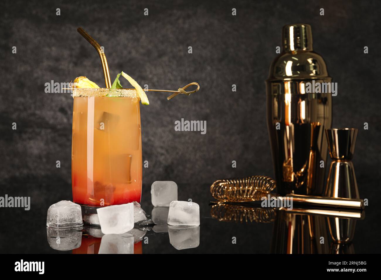 Tasty pineapple cocktail with ice cubes, shaker, bar strainer and ...