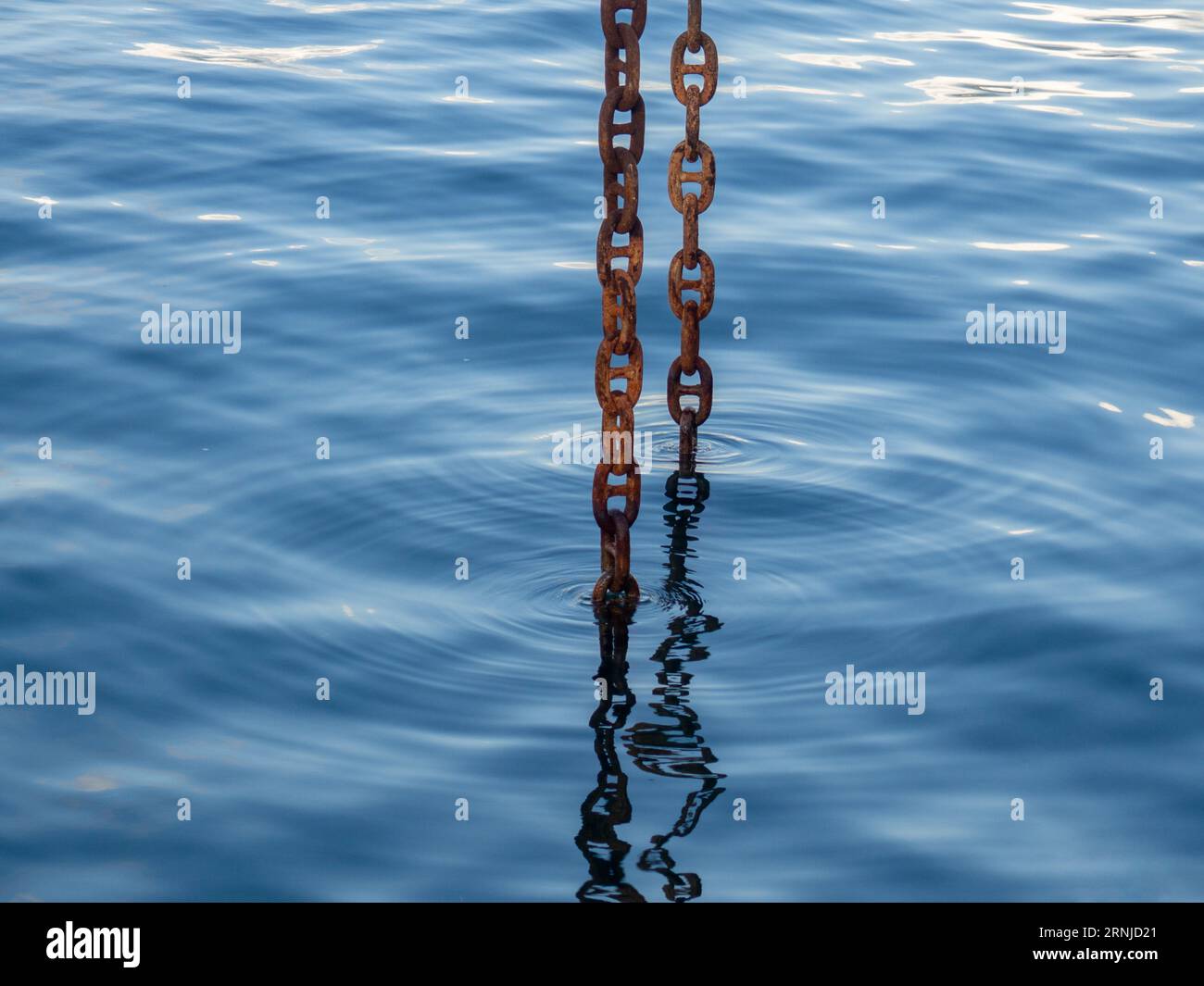 Powerful metal chain going into the water. Deep sea work. An industrial ...