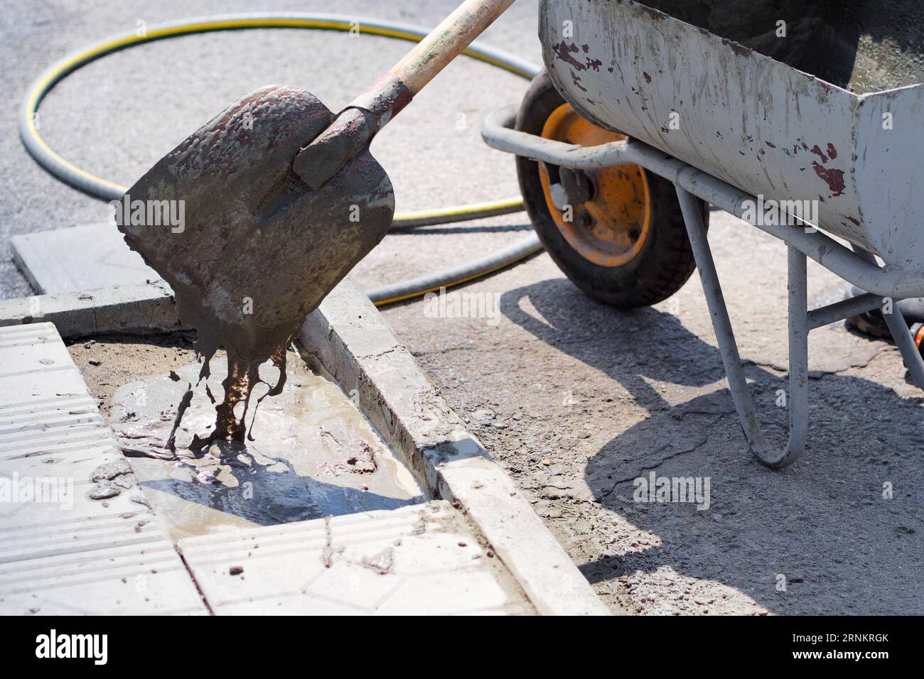 Worker lays foundation tiles of house. View of shovel with liquid ...