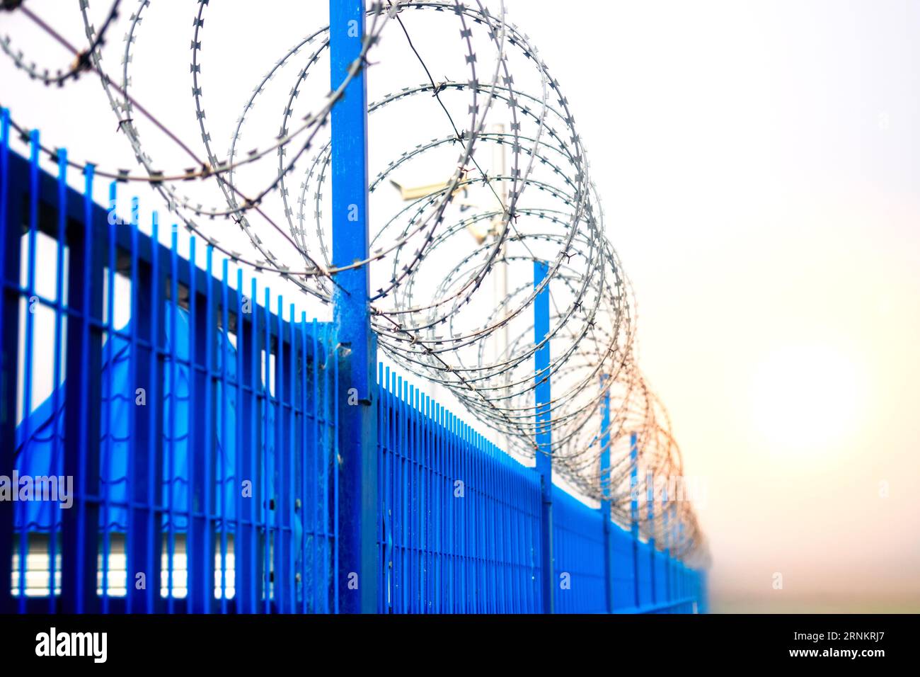 Blue metal fence with barbed wire on top. Fencing around perimeter ...