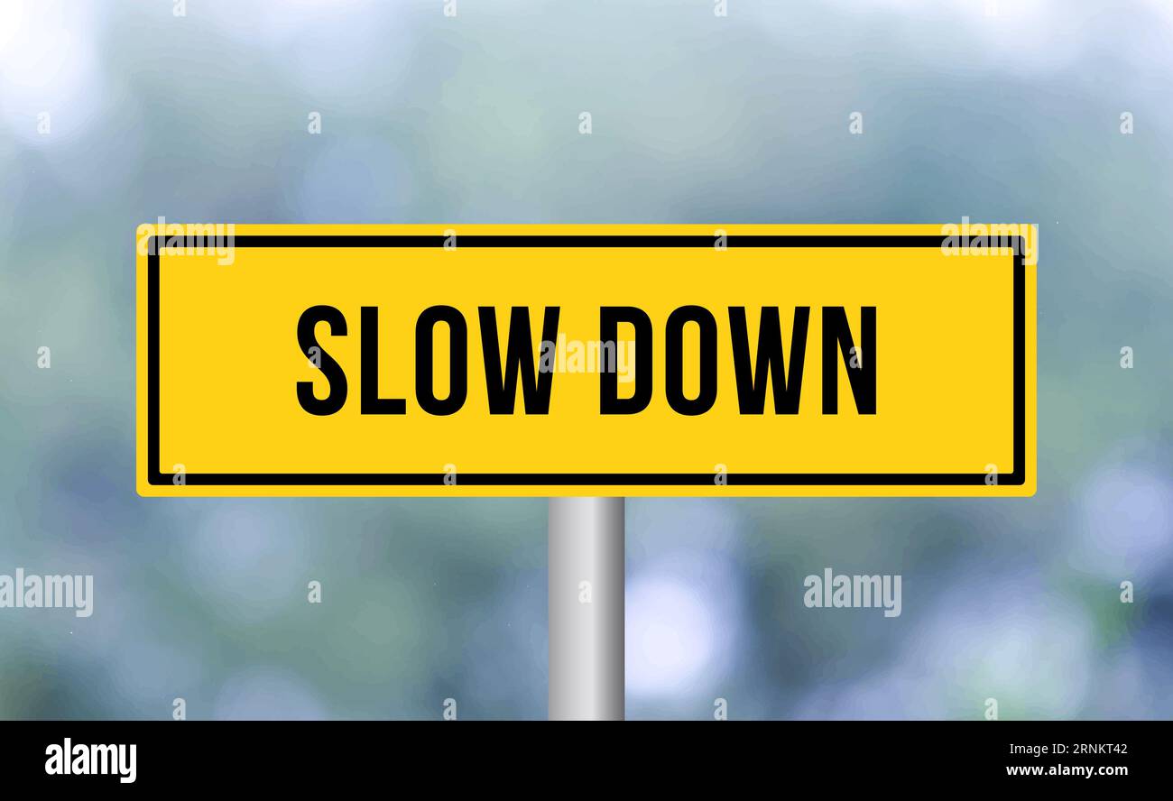 Slow down road sign on blur background Stock Photo - Alamy