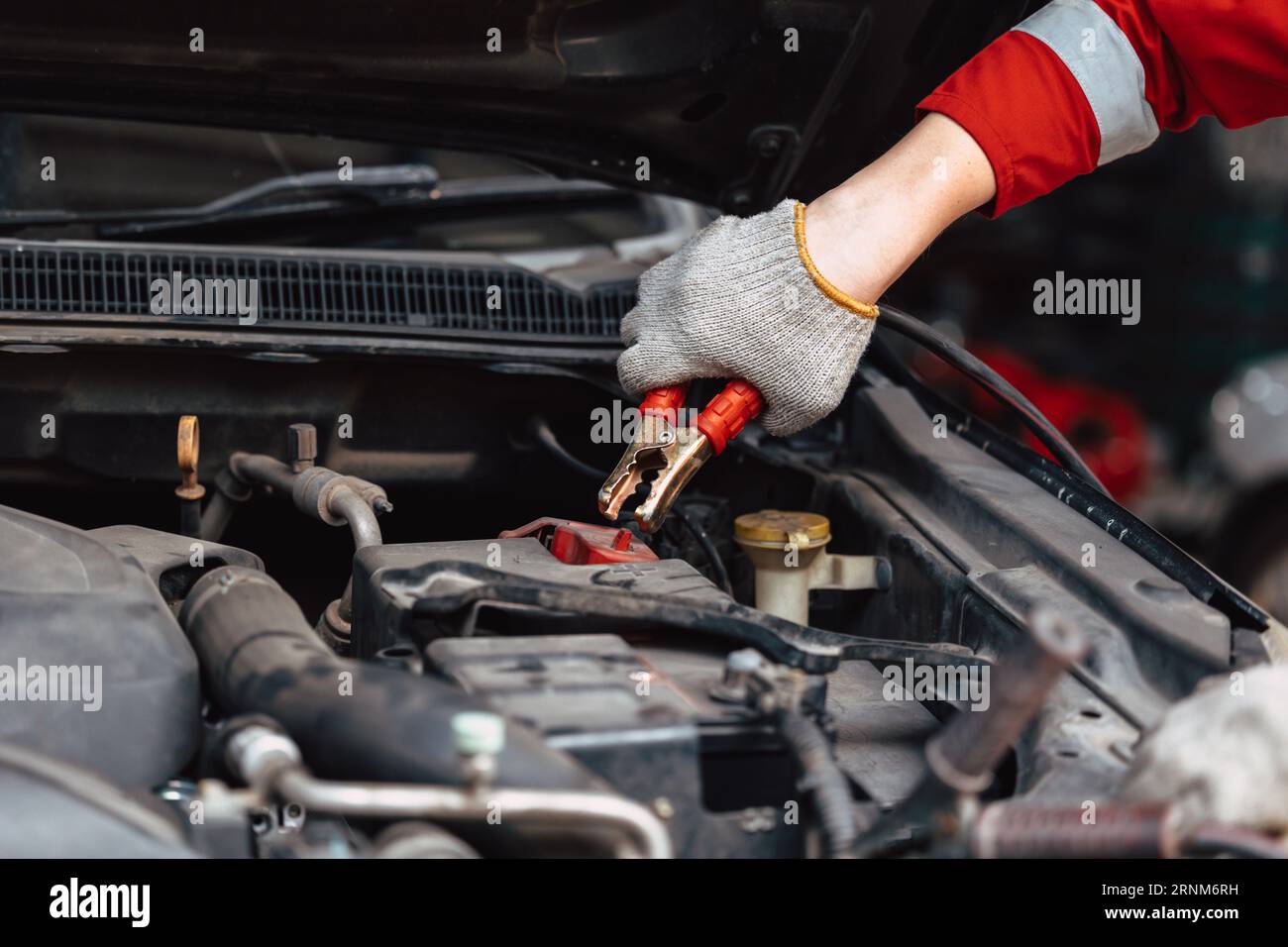 closeup mechanic male hand holding battery clamps grip for charging car ...