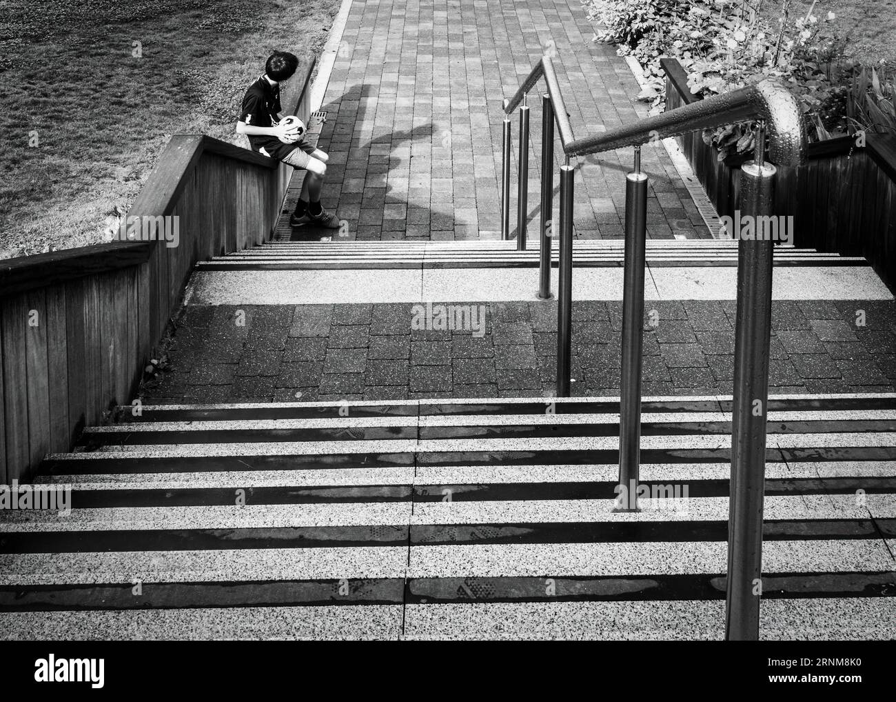 A black and white image of a young boy in a football shirt with a ball ...