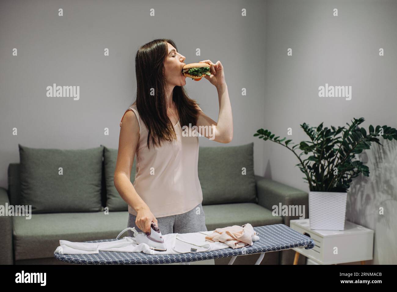A woman has a quick breakfast while doing household chores. A woman ...