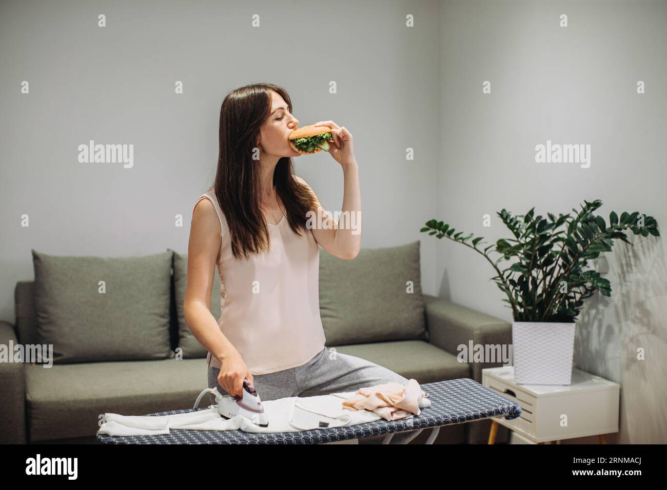 A woman has a quick breakfast while doing household chores. A woman ...