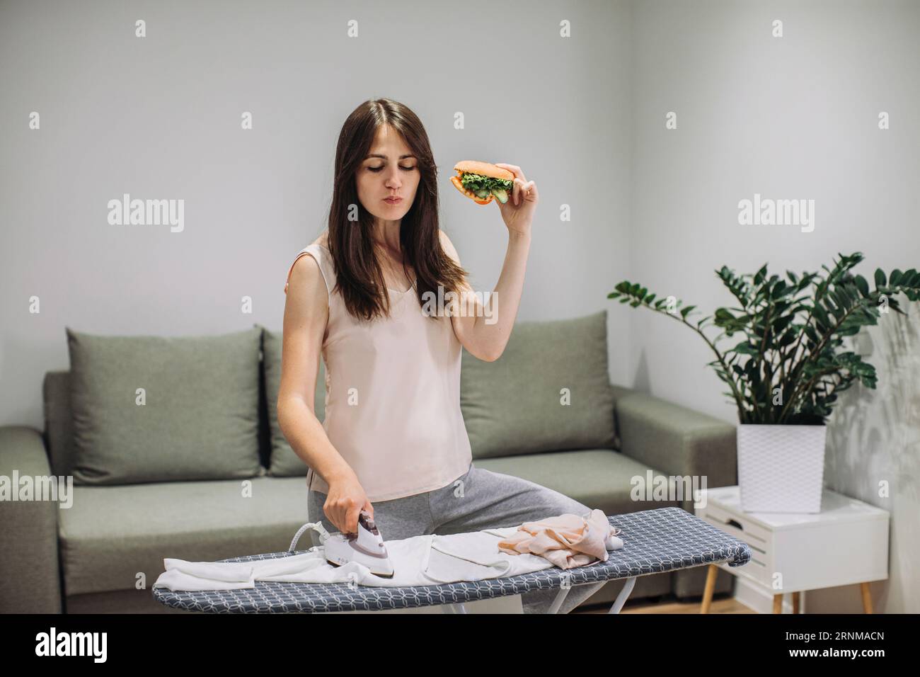 A woman has a quick breakfast while doing household chores. A woman ...