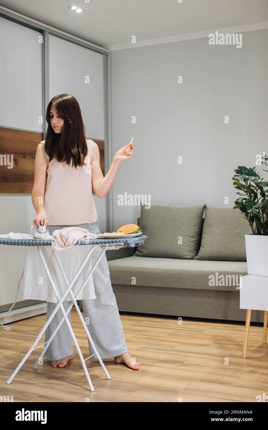 A woman has a quick breakfast while doing household chores. A woman ...