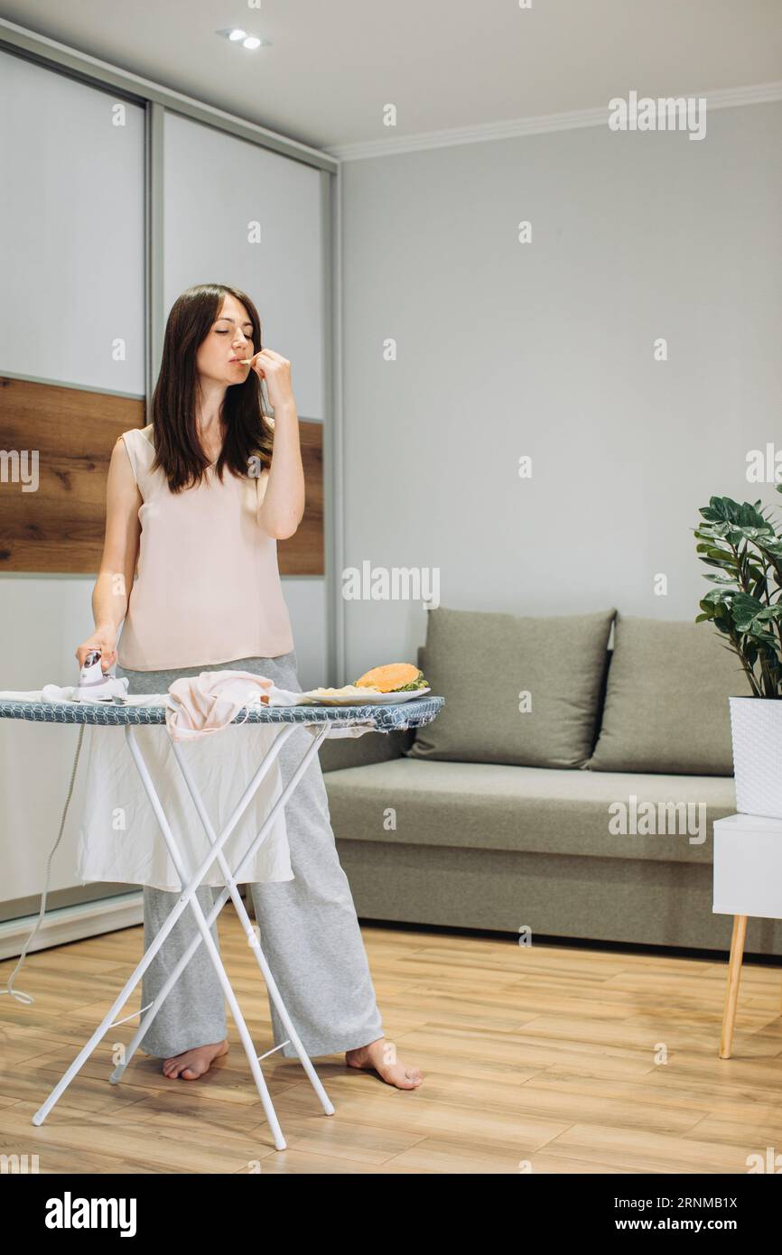 A woman has a quick breakfast while doing household chores. A woman ...