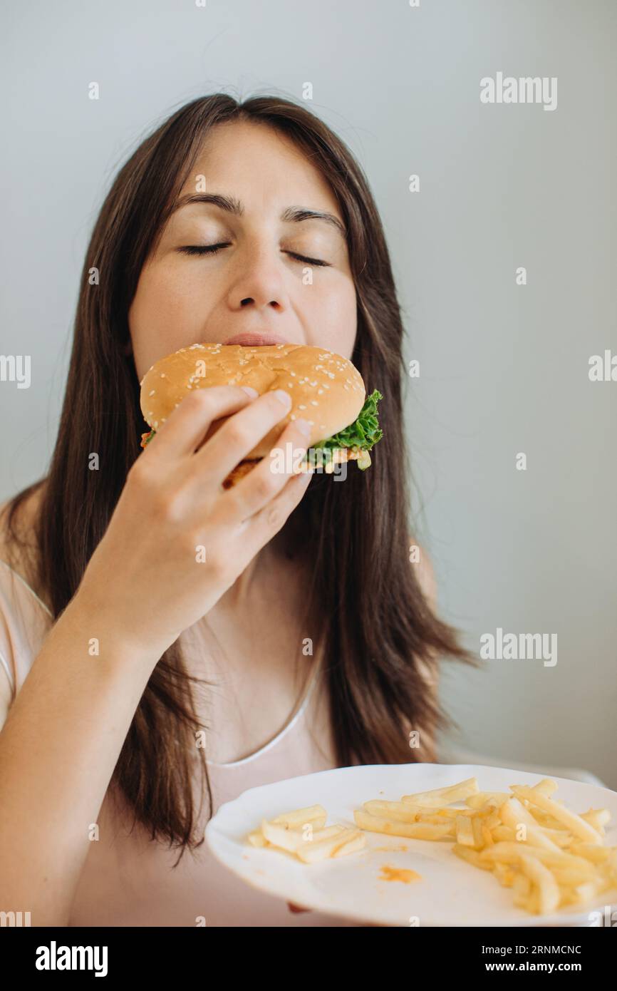 A beautiful young brunette woman is eating a tasty hamburger Stock ...