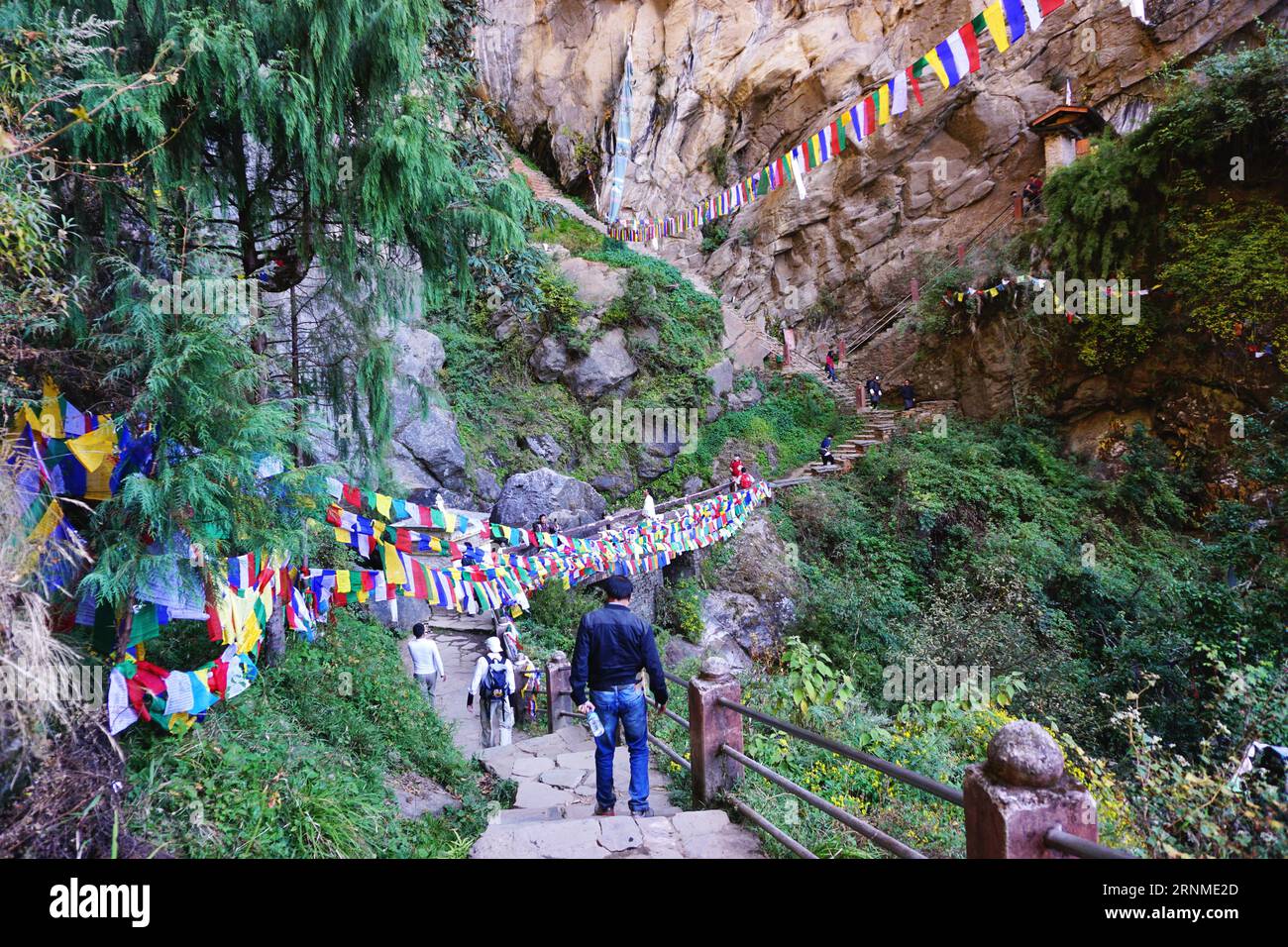Hikers walk toward colorful prayer flags over the trail as they ...