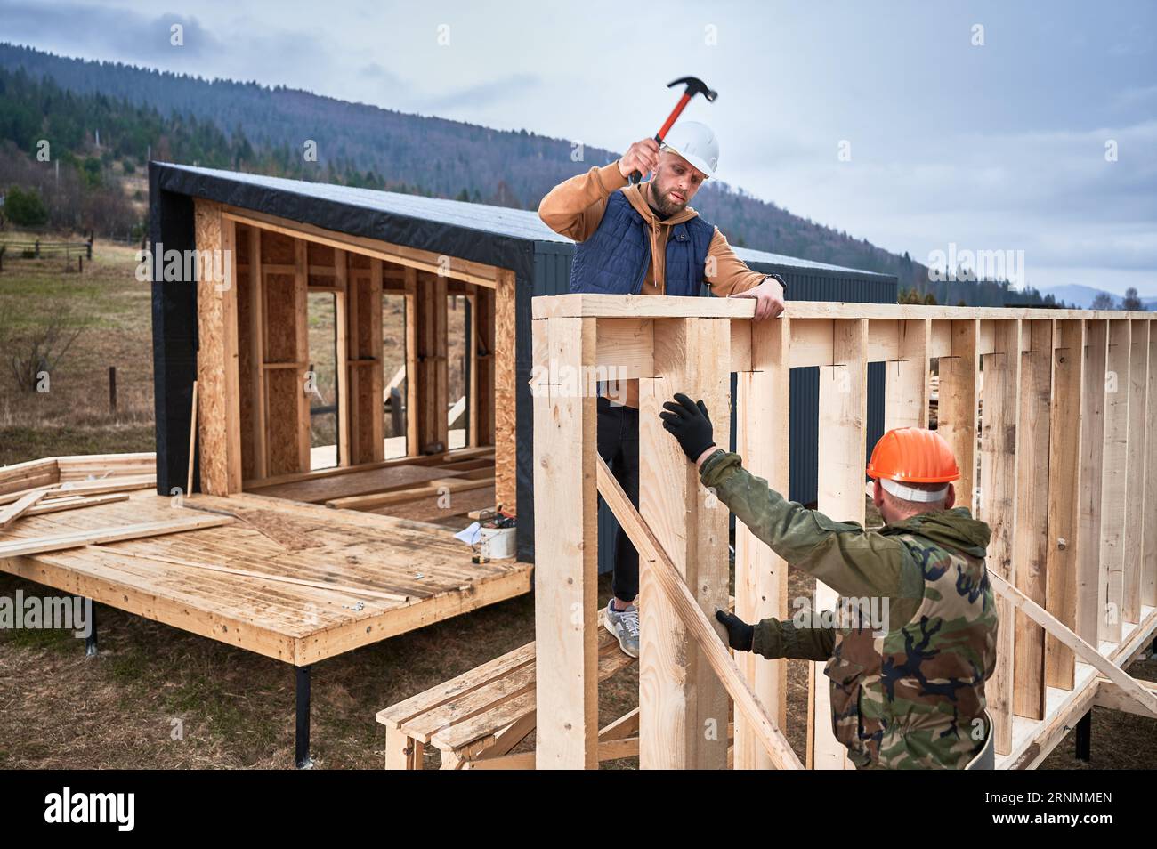 Man worker building wooden frame house on pile foundation. Carpenter ...