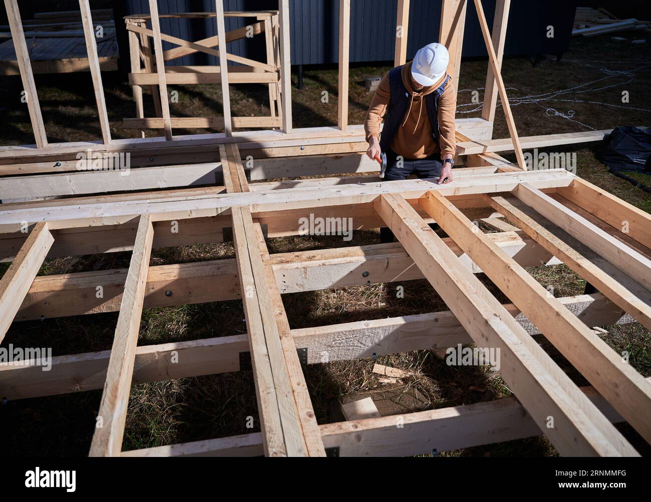 Man worker building wooden frame house on pile foundation. Carpenter ...