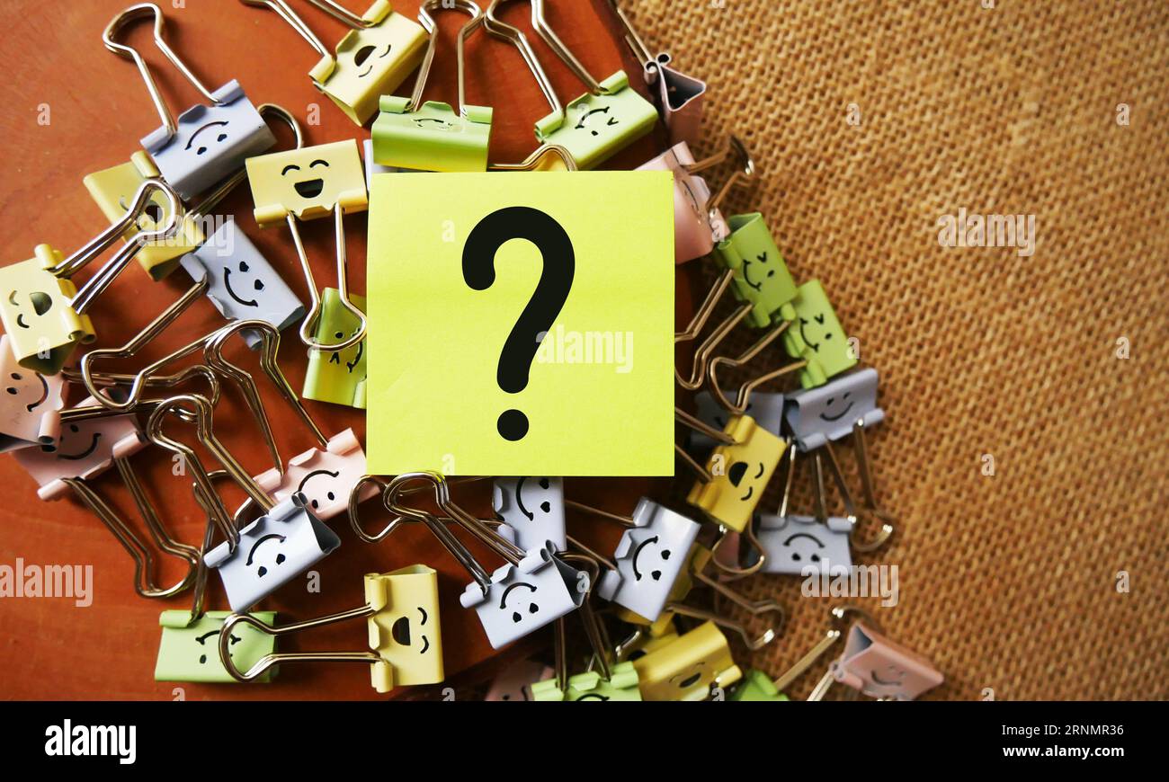 Question marks piled up on burlap background with funny paper clips ...