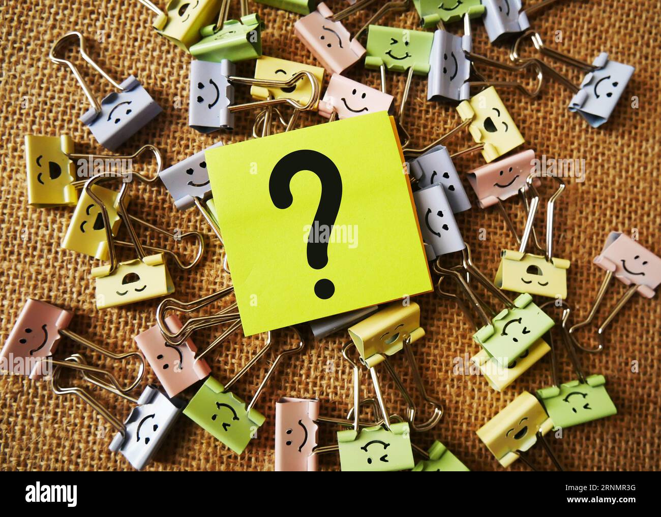 Question marks piled up on burlap background with funny paper clips ...