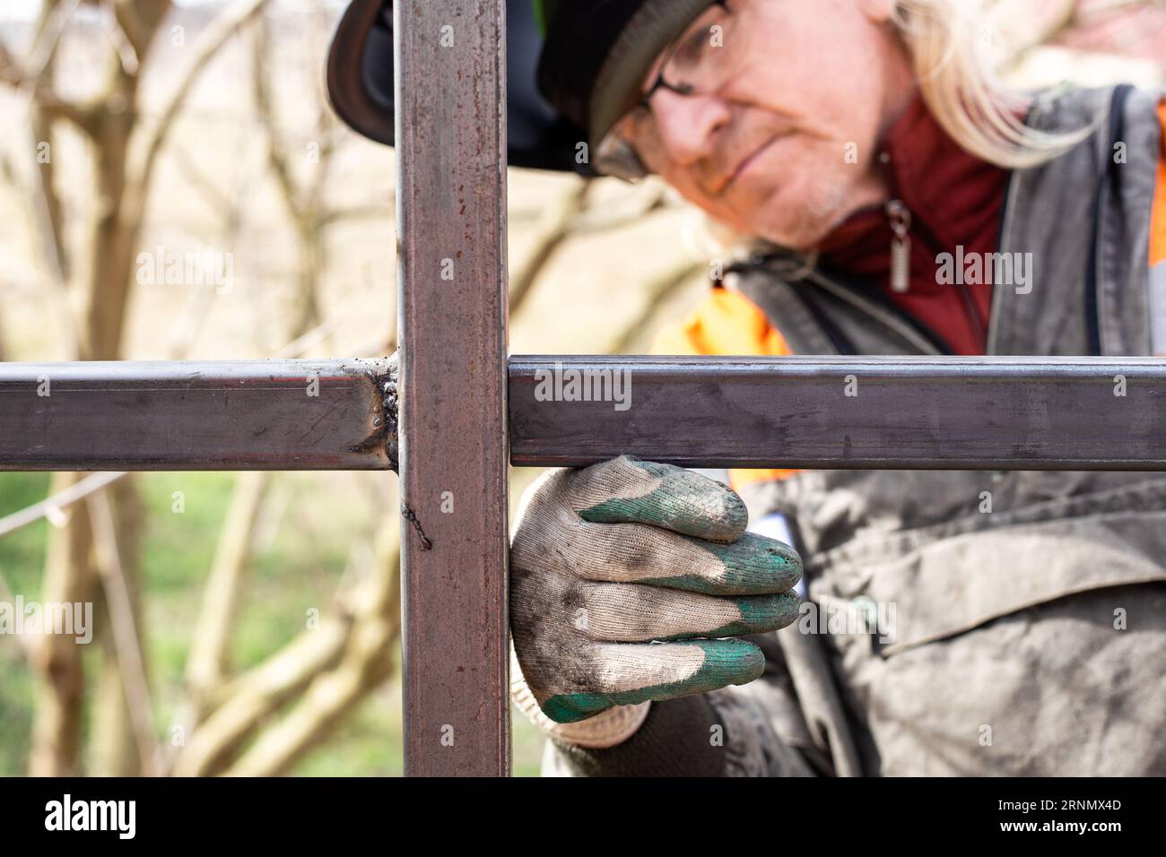 welder tries on a profile pipe on a metal structure for welding with an ...
