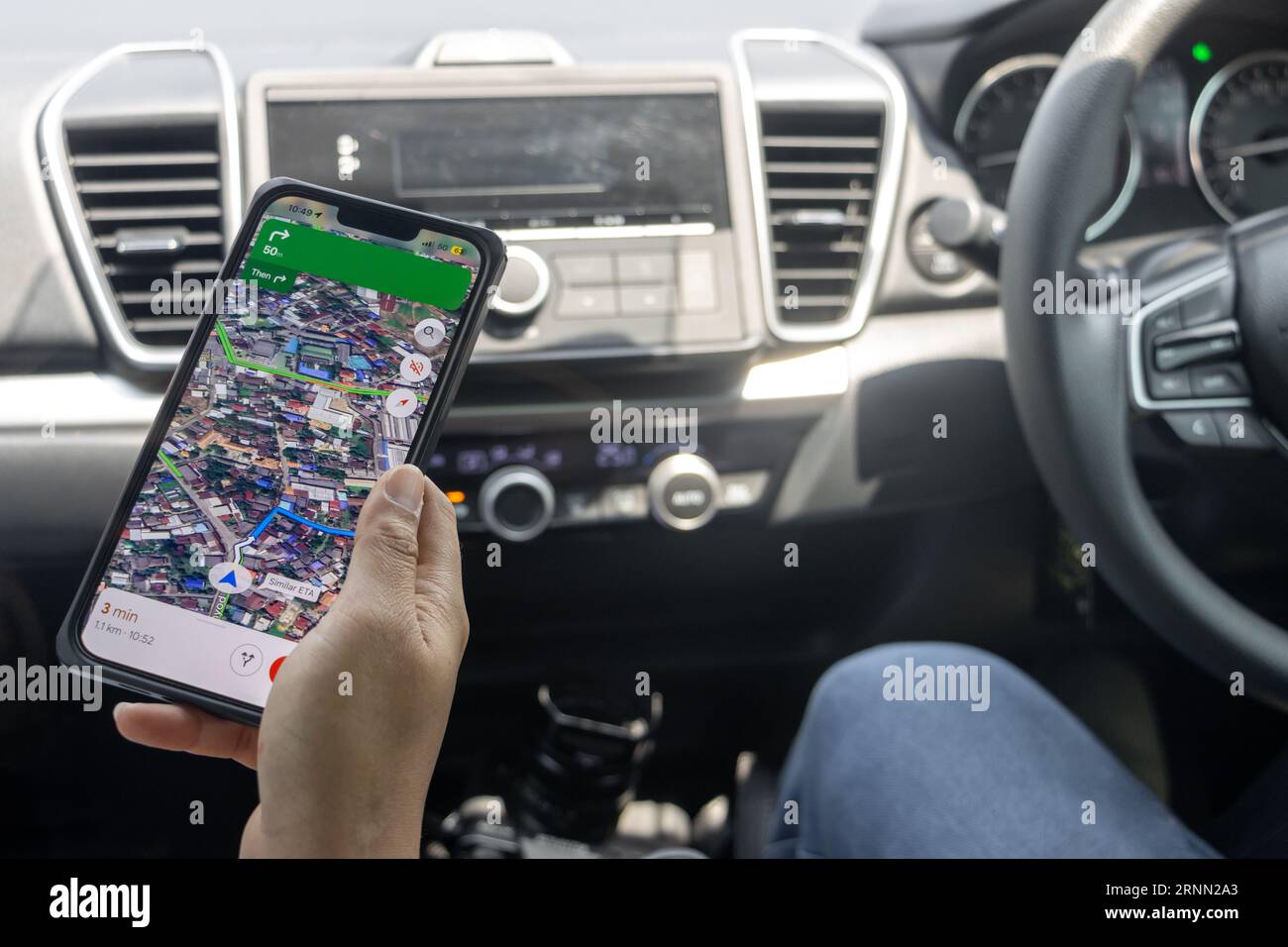 A woman is holding a phone with navigation in a moving car driven by a ...
