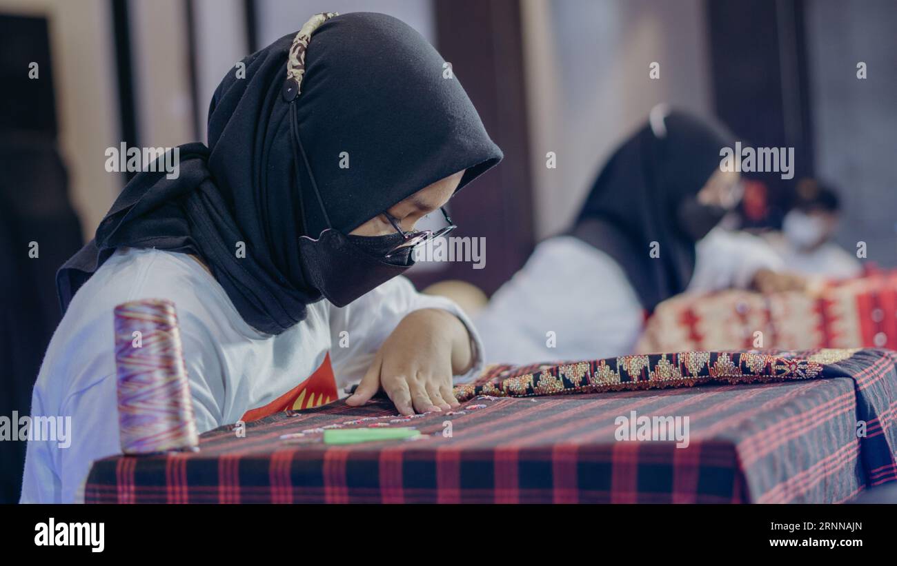 A woman is weaving cloth, or so-called traditional tapis cloth Stock ...
