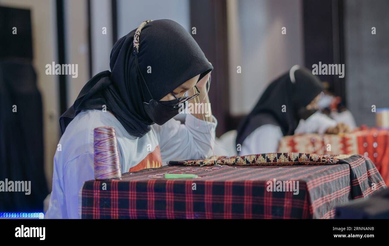 A woman is weaving cloth, or so-called traditional tapis cloth Stock ...