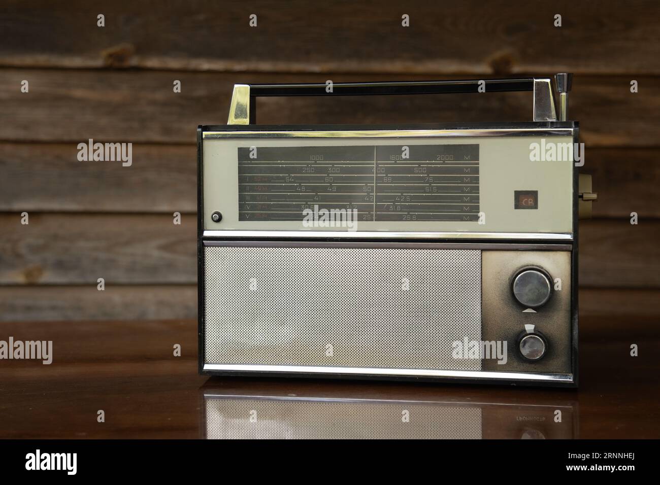 Vintage radio receiver from 1970s stands on a old polished table with a ...