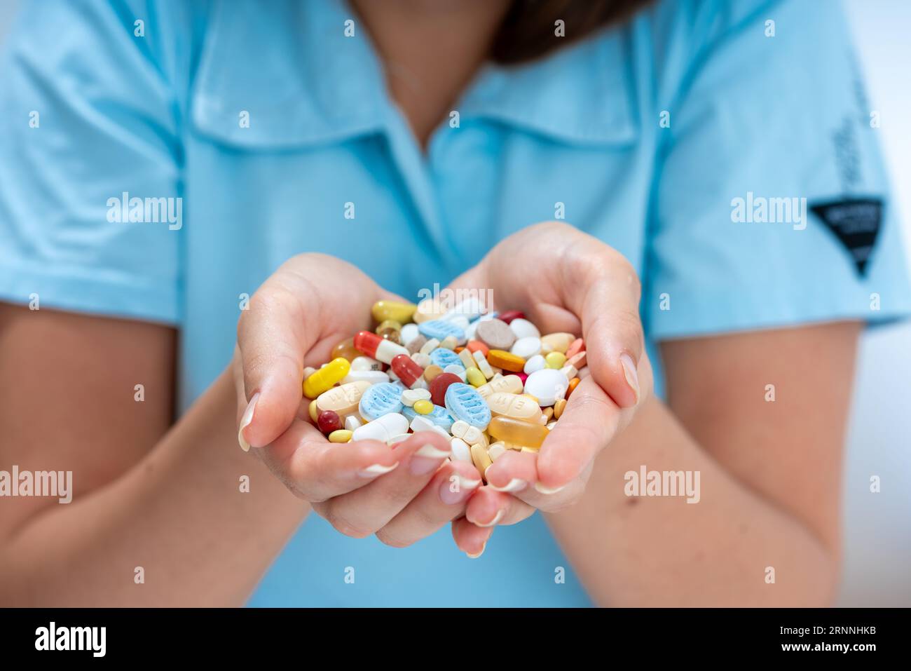 A woman is holding a pile of pills in her hand. She looks worried and ...