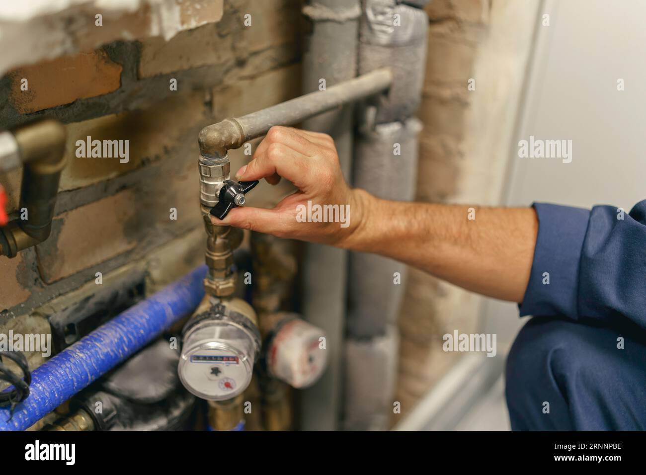 Plumber hand is going to turn off the valve of water pipe before ...