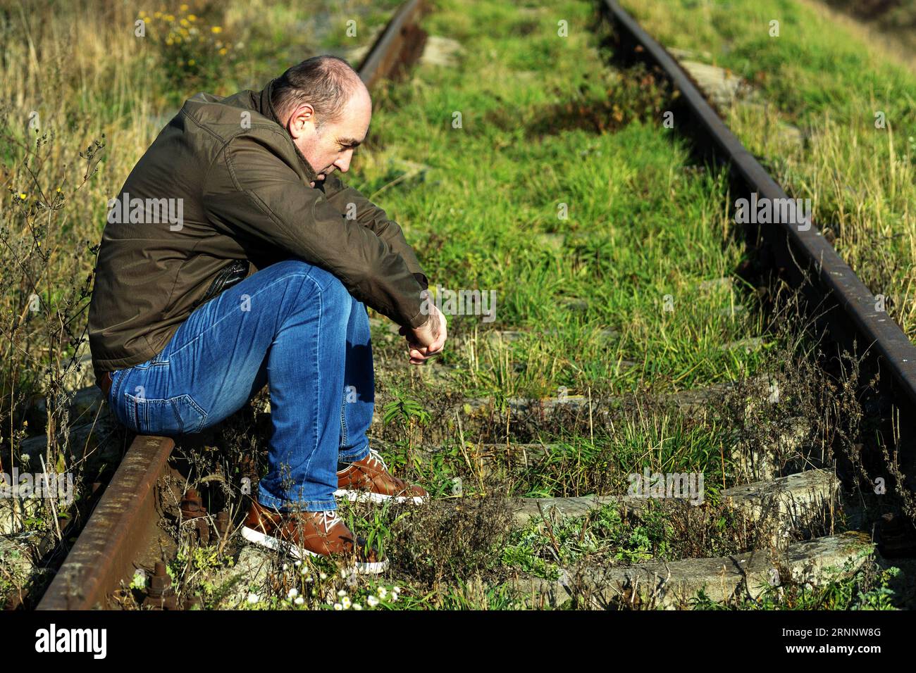 The thoughtful man sits on rails. The upset person in a stress. Concept ...