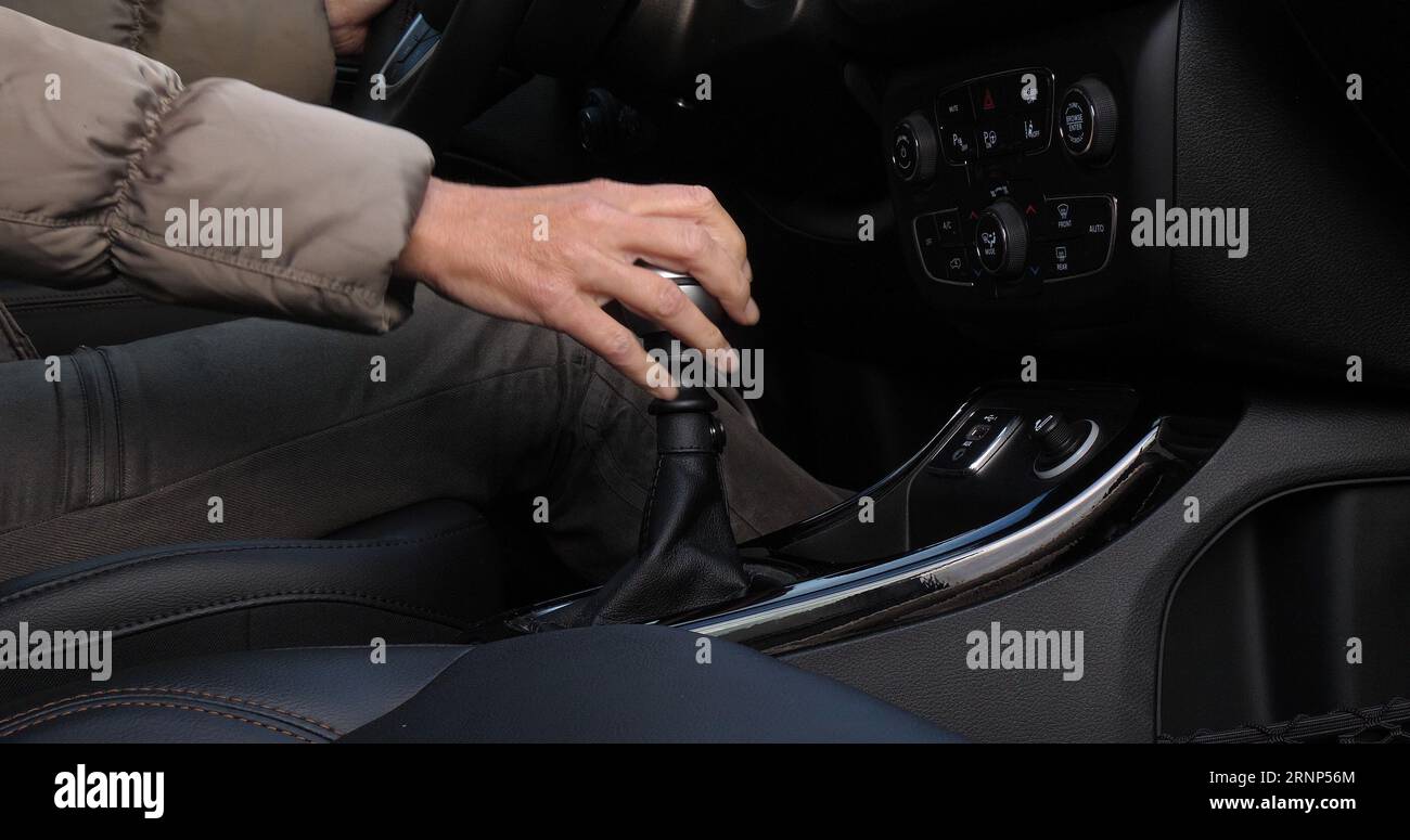 Woman in a car putting her hand on the gear lever to change the engine ...