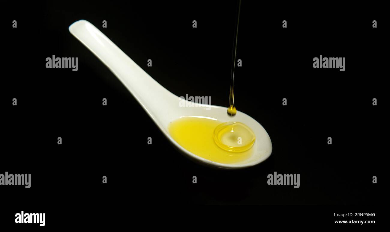 Olive Oil, Falling in a Spoon against Black Background Stock Photo - Alamy