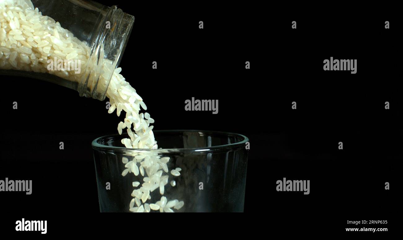 Rice falling against Black Background Stock Photo - Alamy