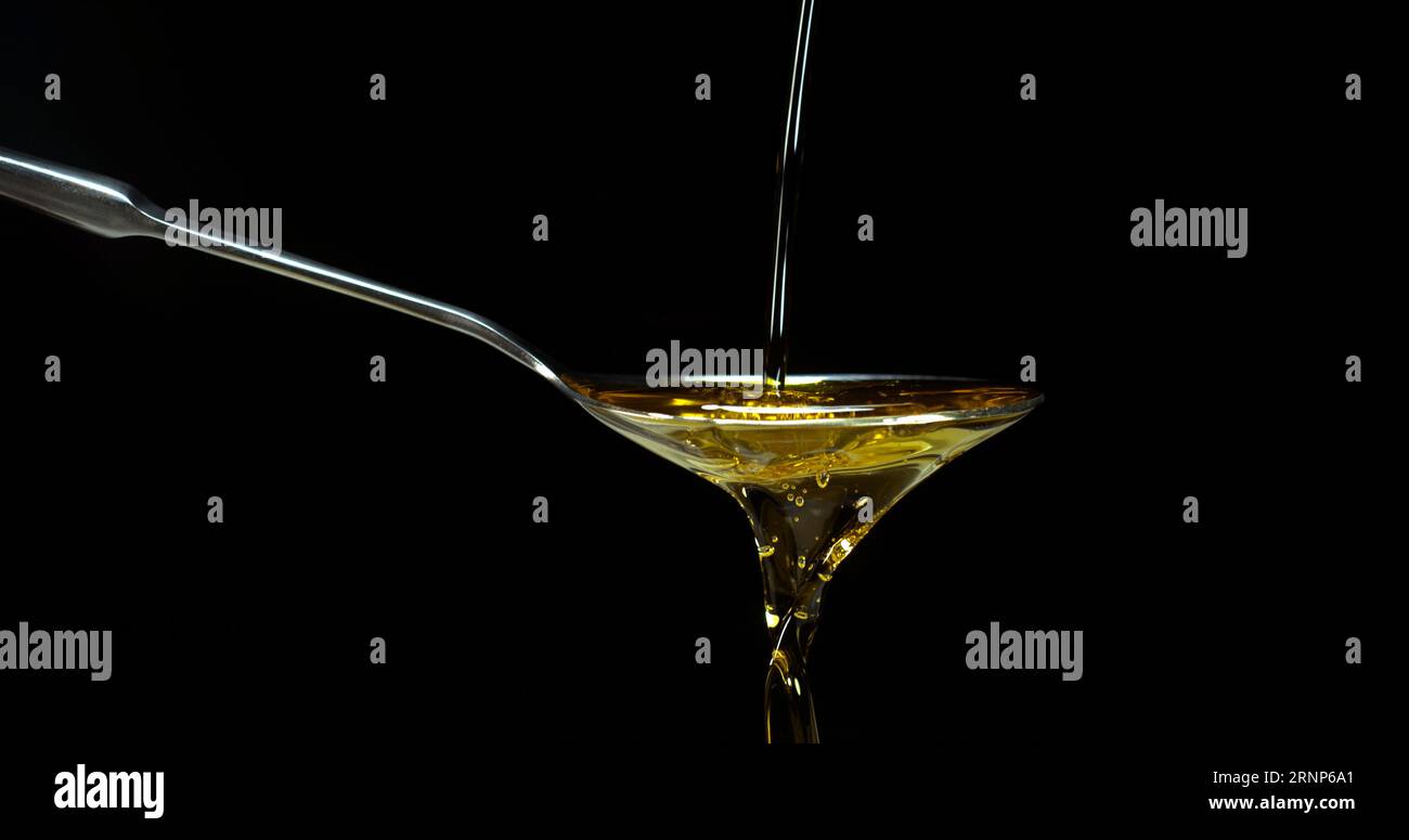 Olive Oil, Falling in a Spoon against Black Background Stock Photo - Alamy