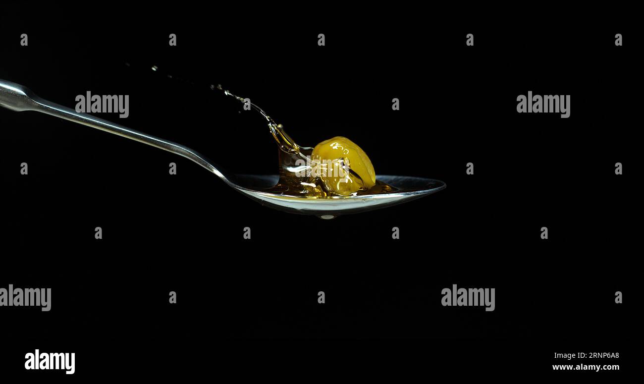 Green Olive, Olea europaea, Falling in a Spoon against Black Background ...