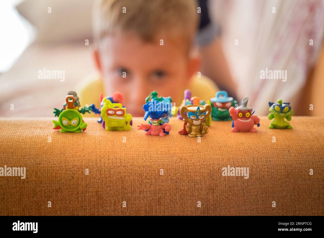 Cute little boy with blond hair staring and playing with his super ...