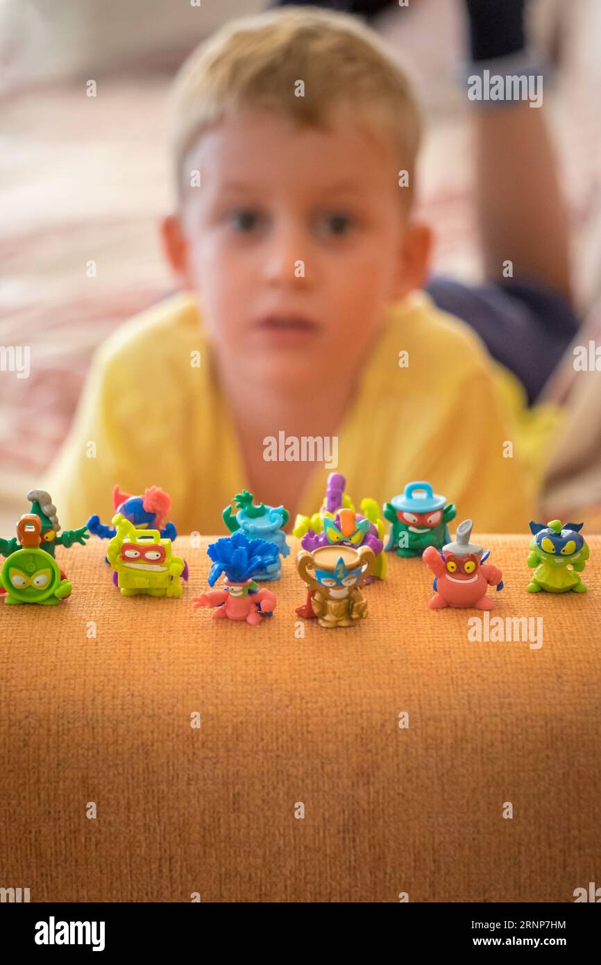Cute little boy with blond hair staring and playing with his super ...