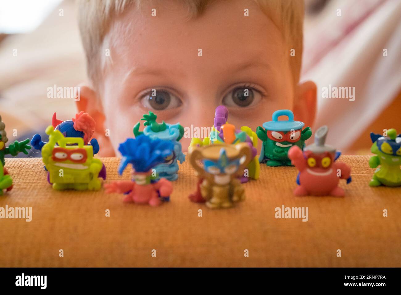 Cute little boy with blond hair staring and playing with his super ...