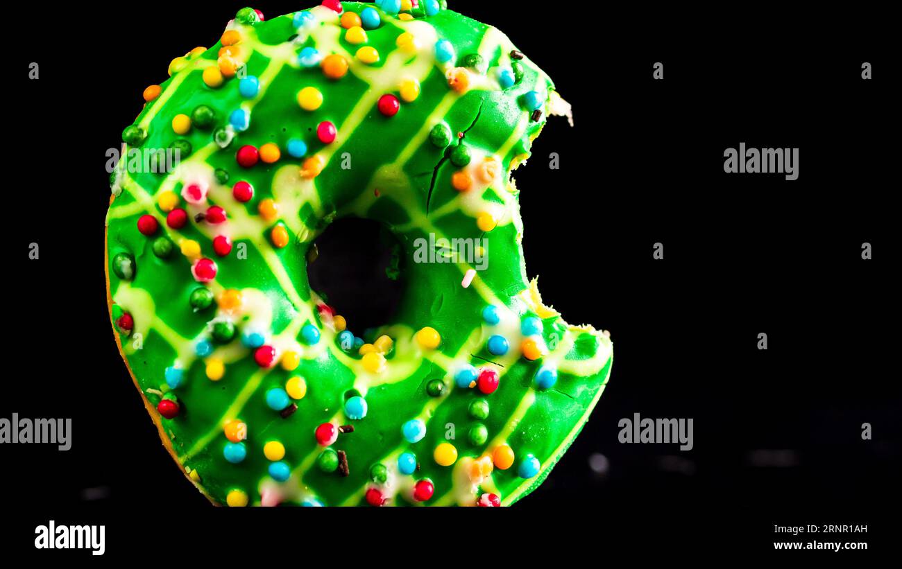 Green glazed donut with sprinkles isolated. Close up of colorful bitten donut Stock Photo - Alamy