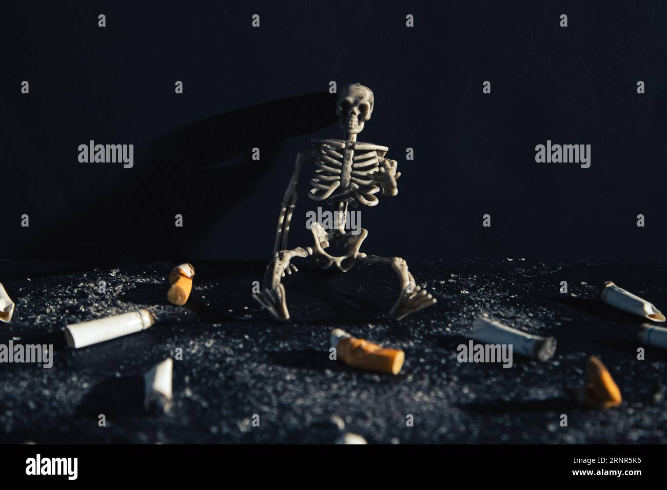 Human skeleton sits with a cigarette in a dark room. Anti-tobacco ...