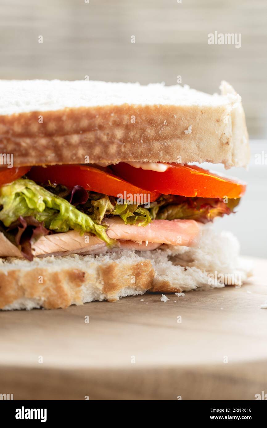 A close up of the fresh filling of a ham and salad sandwich with tomato ...
