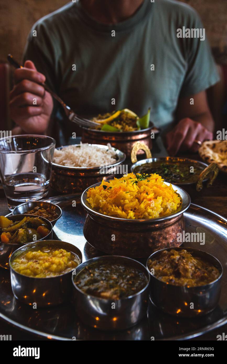 Man eating traditional food in an Indian restaurant. Vegetarian Thali ...