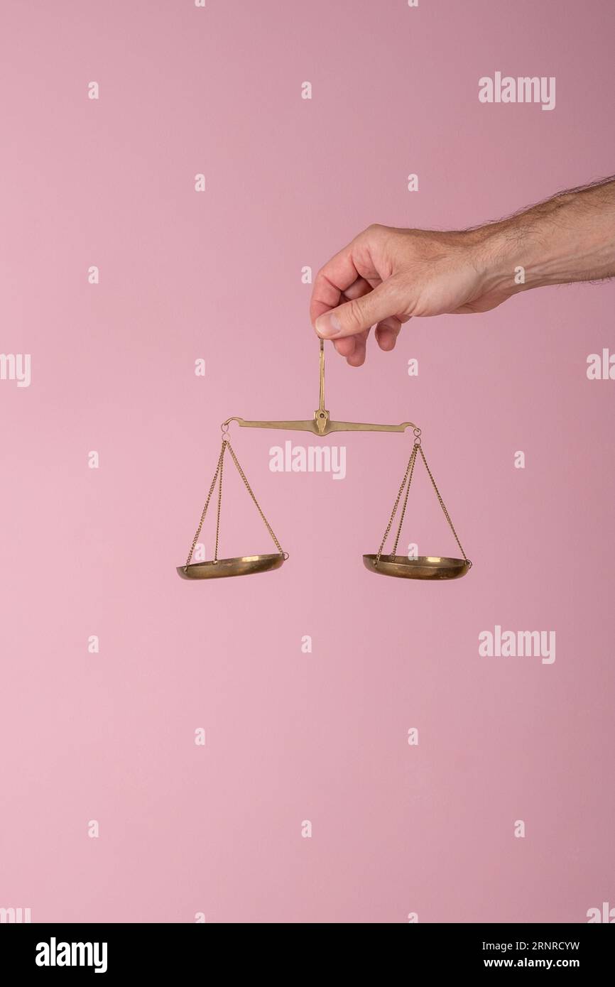 man hand holding a balance on pink background Stock Photo - Alamy