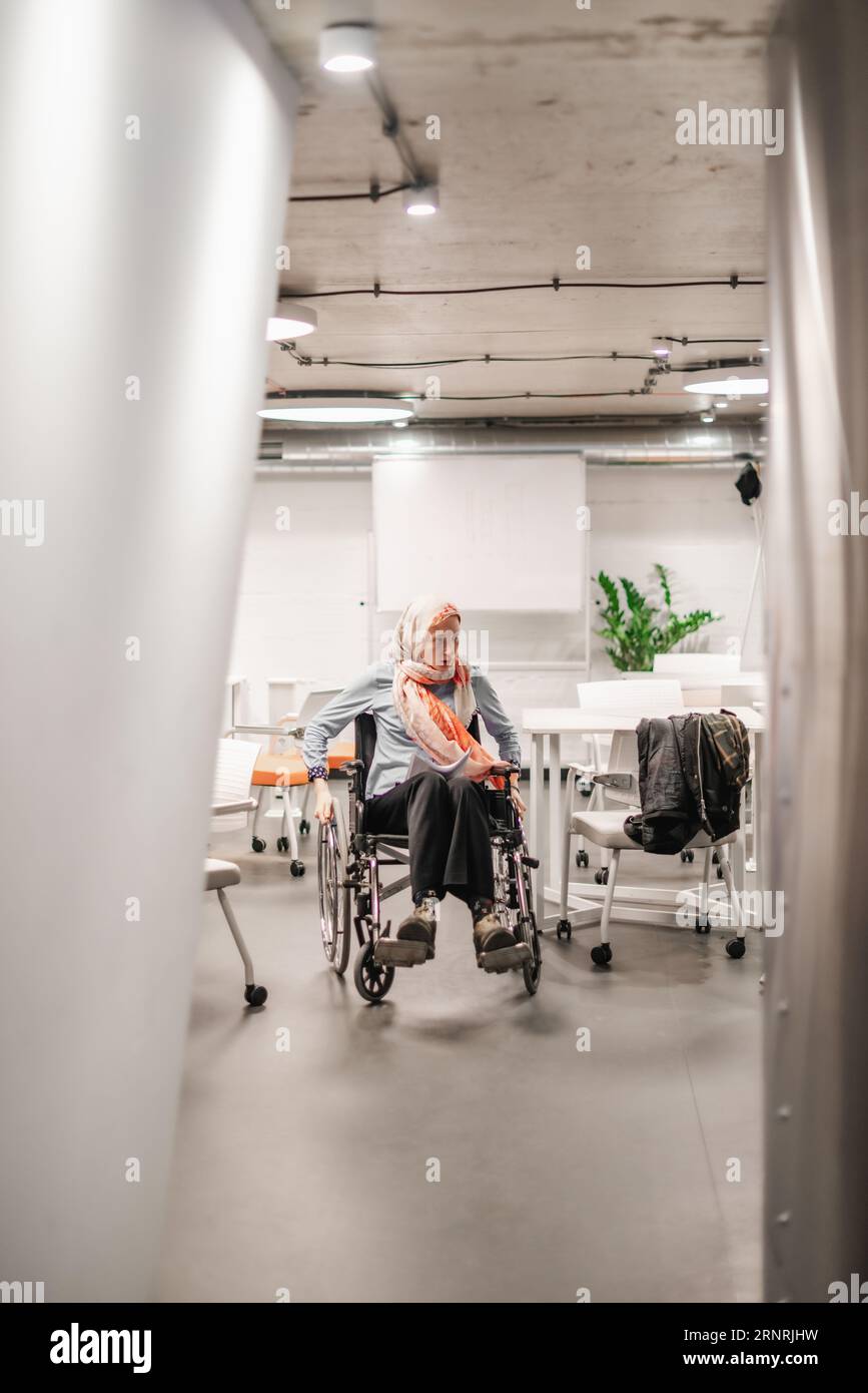 Handicapped woman staring at something while rolling her wheelchair to ...