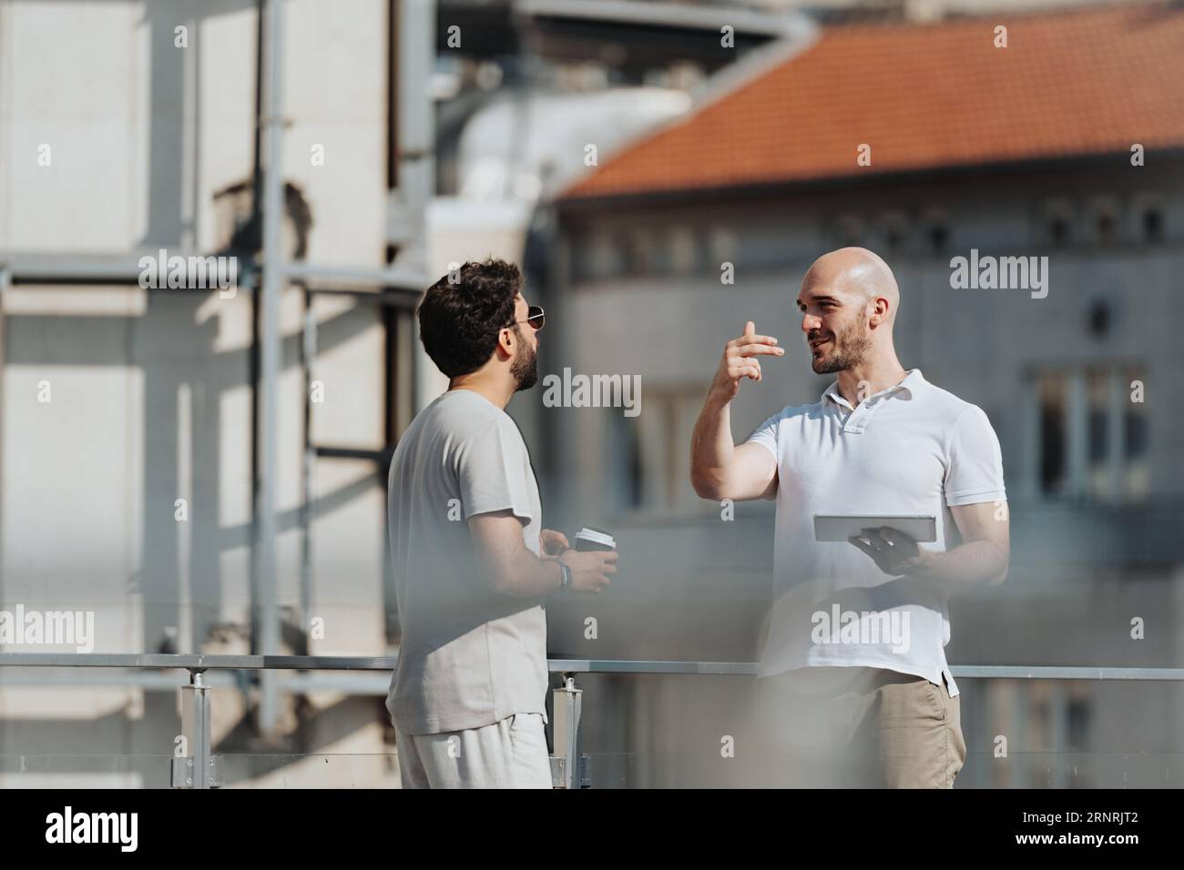 Architects discussing blueprint outdoors with modern buildings as ...