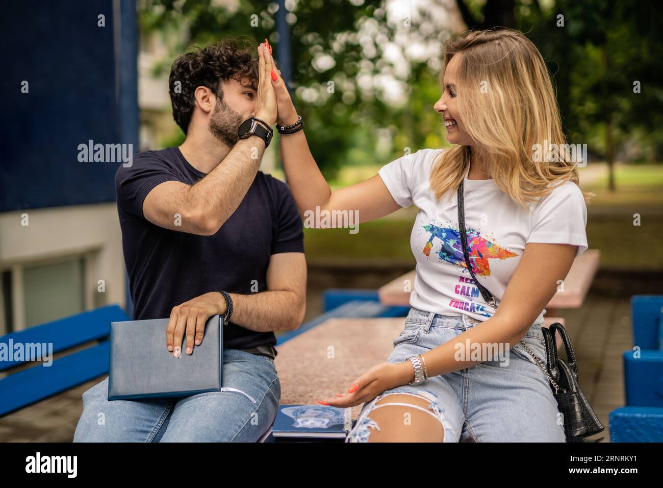 Happy university students giving high five each other and smiling after ...