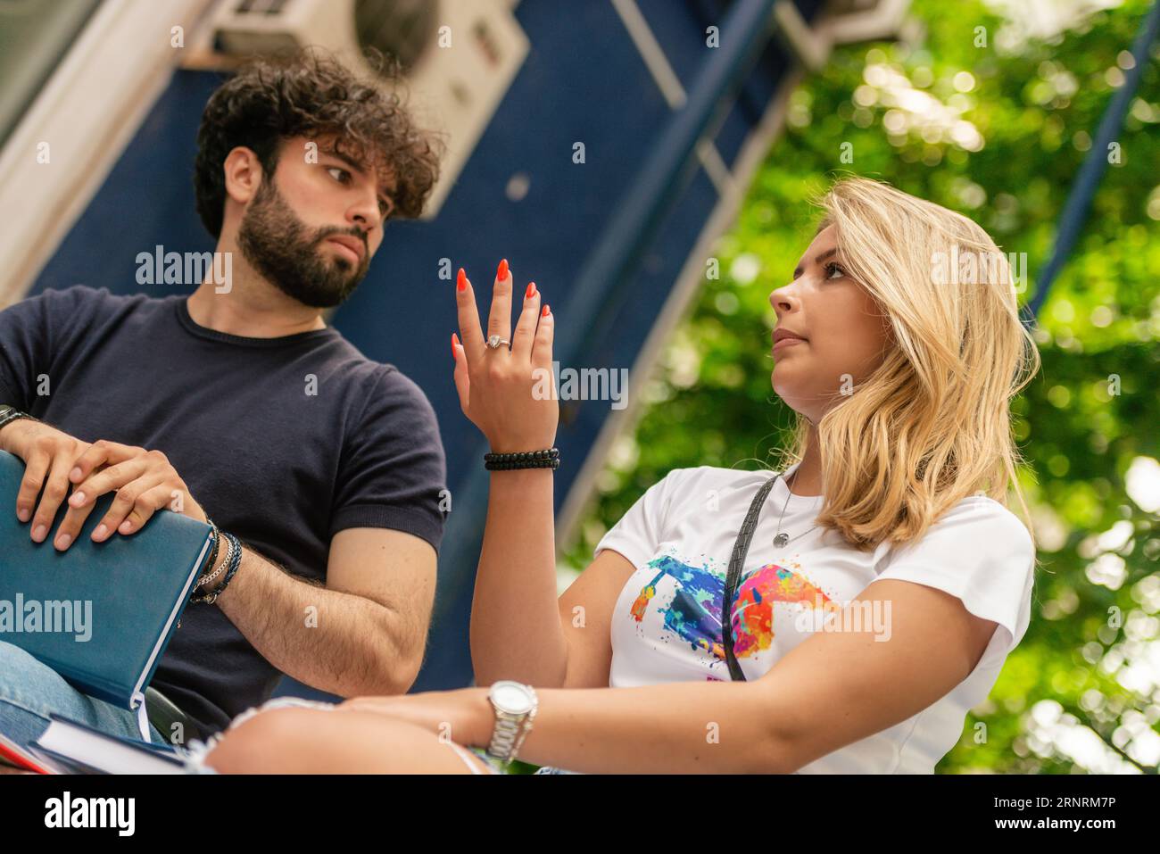 Two friends sitting, smiling and talking outside in the sunlight Stock ...
