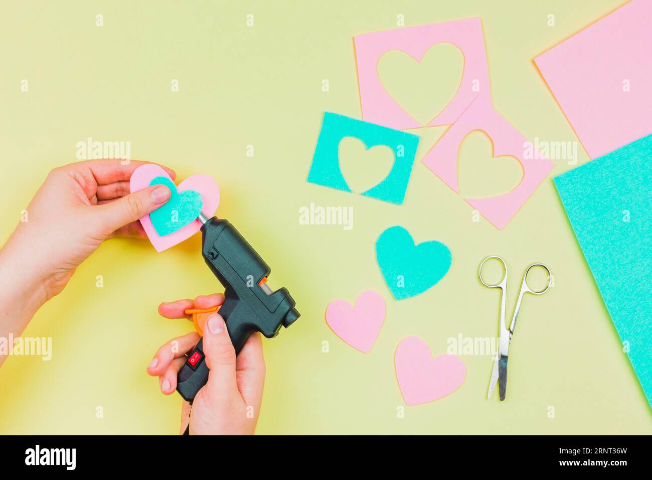 Close up woman s hand sticking paper heart shape with electric hot glue ...