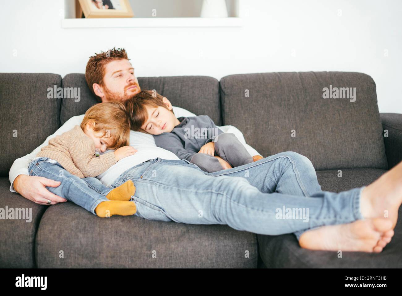 Dad taking nap with sons sofa Stock Photo - Alamy
