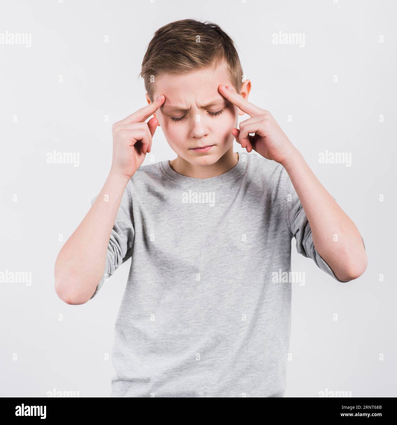 Serious boy having headache standing against white background Stock ...