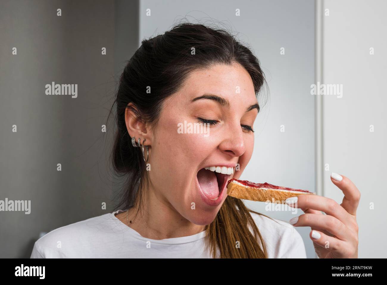 Happy woman eating jam bread Stock Photo - Alamy
