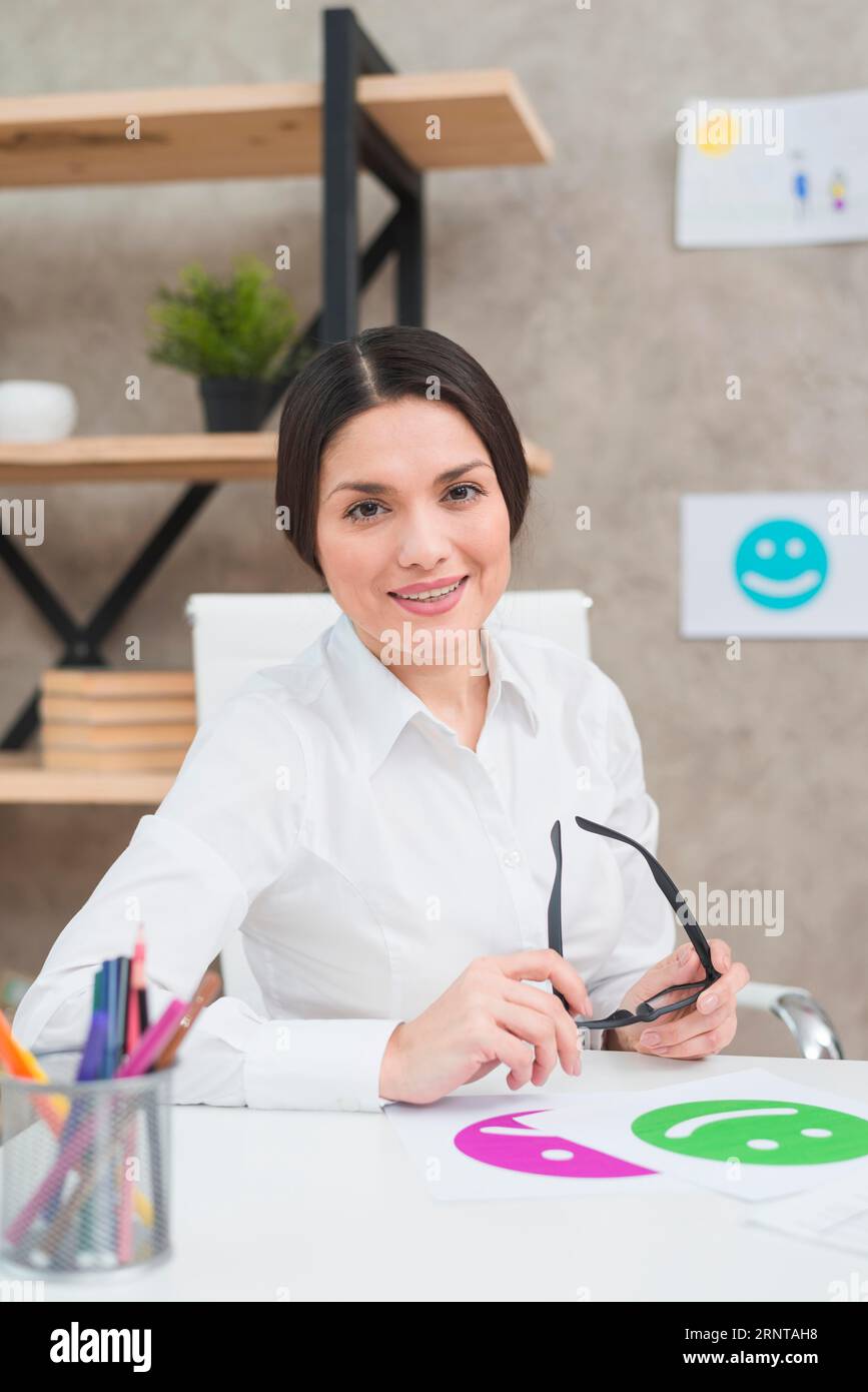 Portrait smiling beautiful female psychologist holding black eyeglasses ...